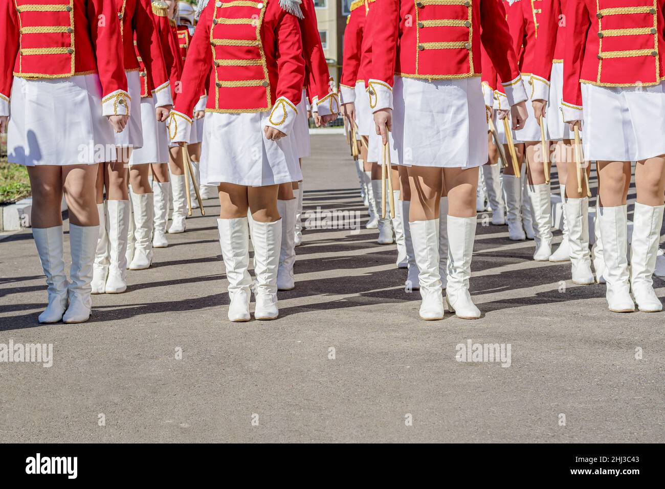 Group of young girls in bright ceremonial suits are marching in even ...
