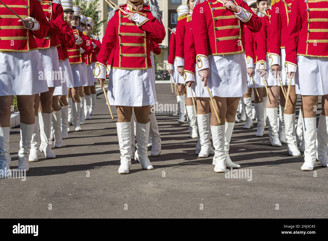 Group of young girls in bright ceremonial suits are marching in even ...