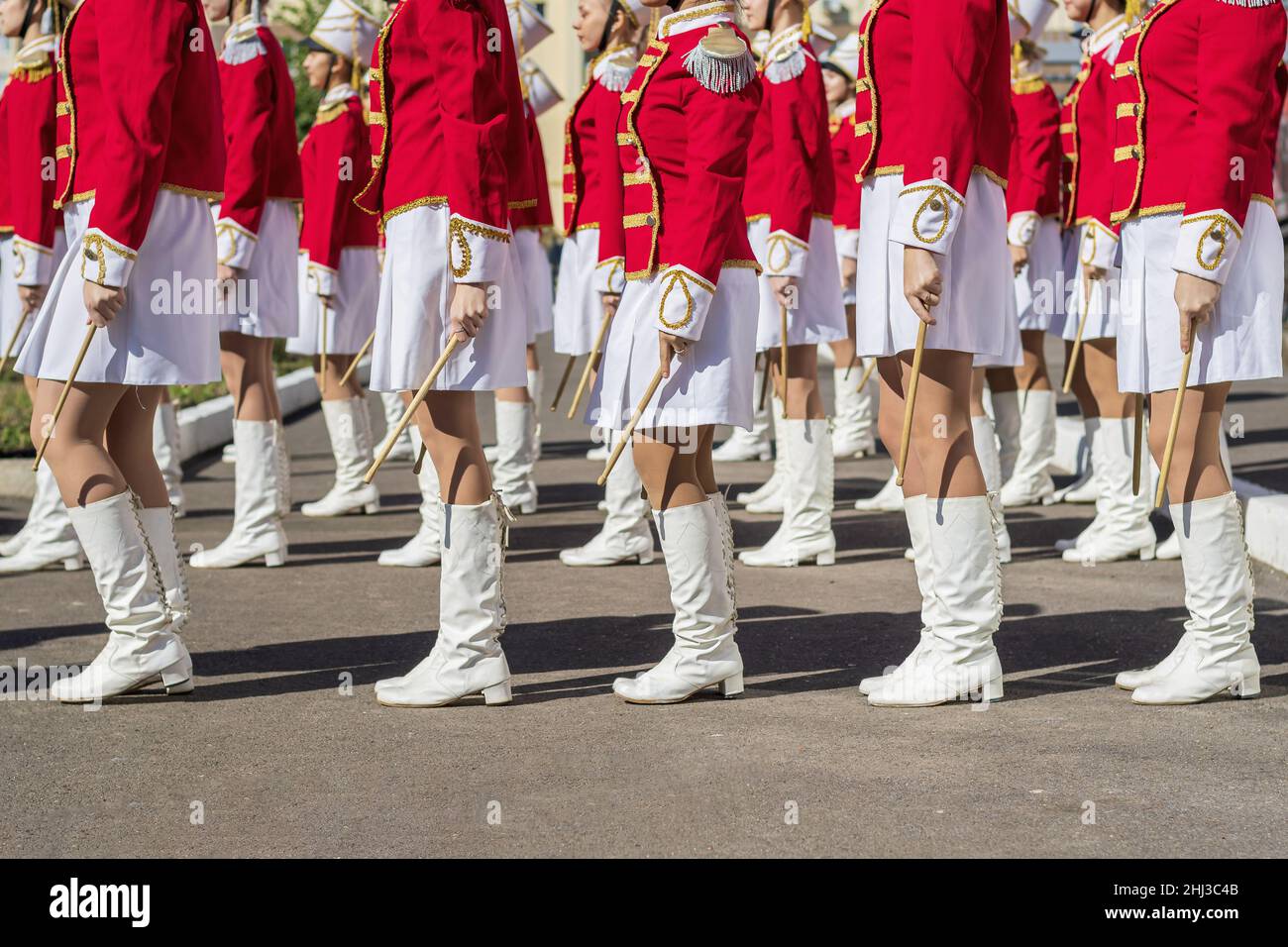 Group of young girls in bright ceremonial suits are marching in even ...