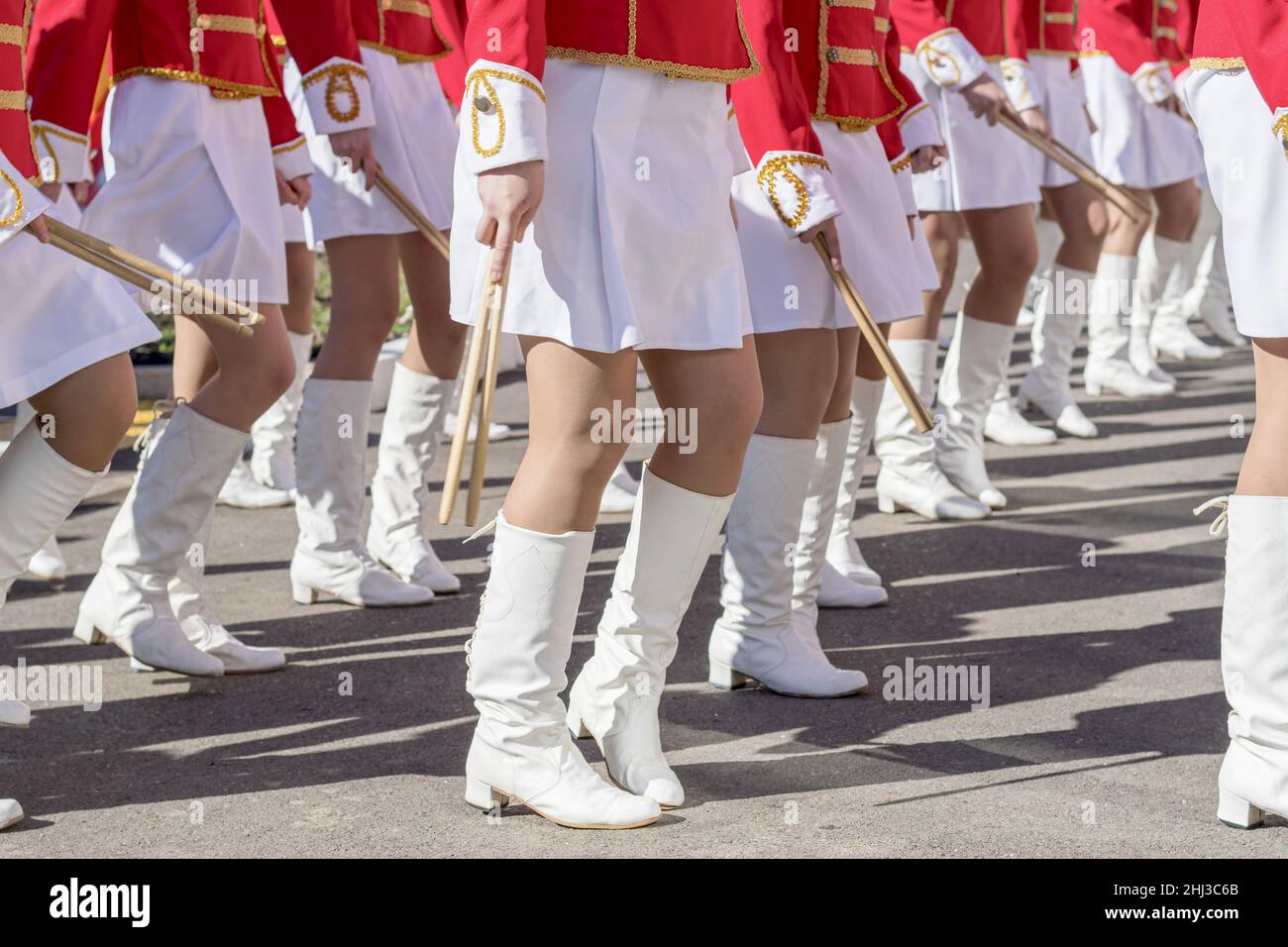 Group of young girls in bright ceremonial suits are marching in even ...