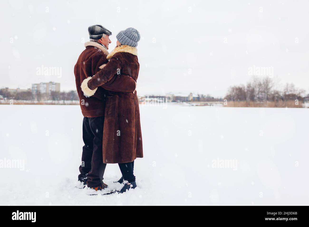 Senior family couple dancing outdoors during snowy winter weather ...