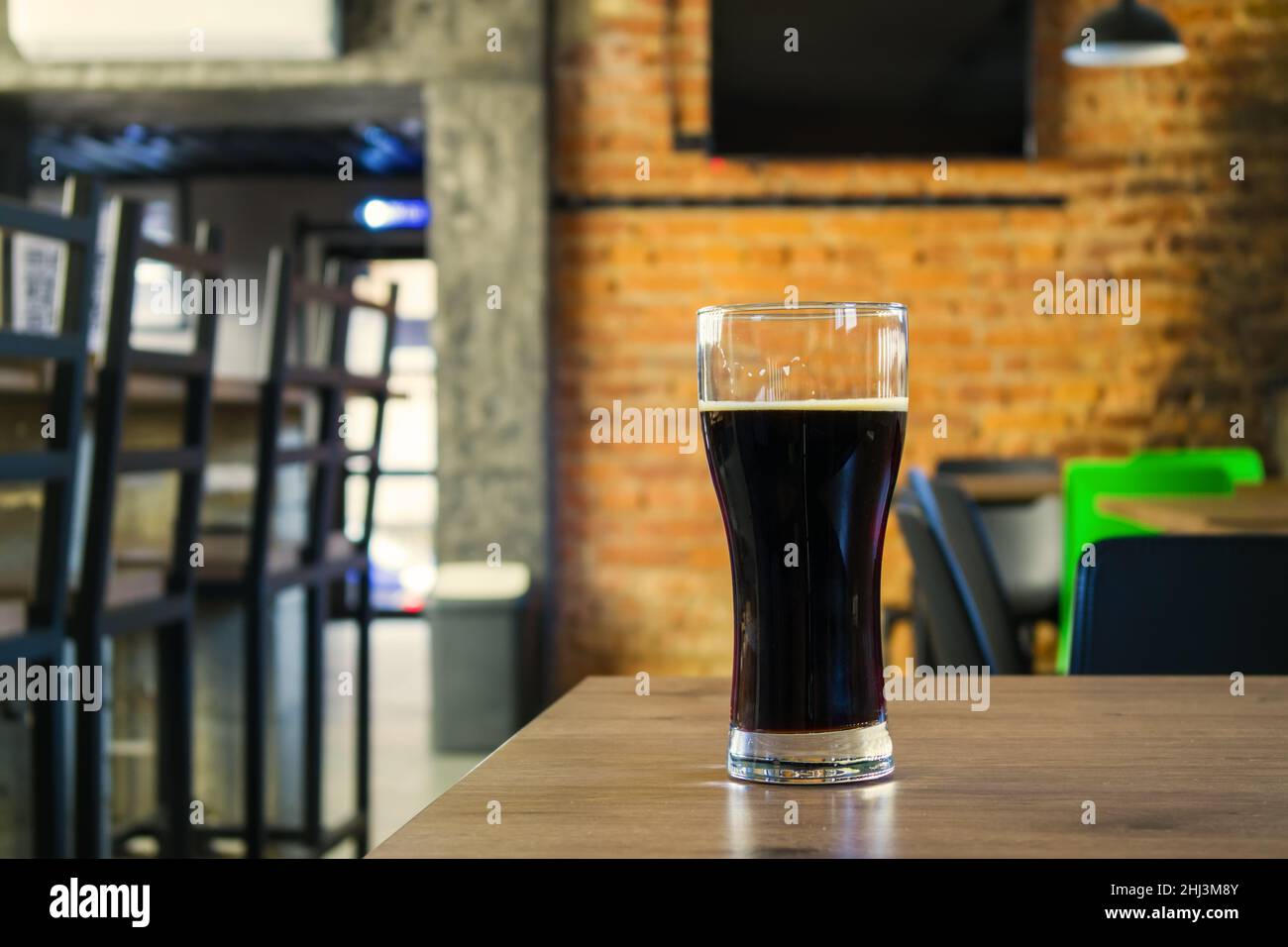 Glass of dark beer on wooden counter in beautiful bar. Glasses of dark ...