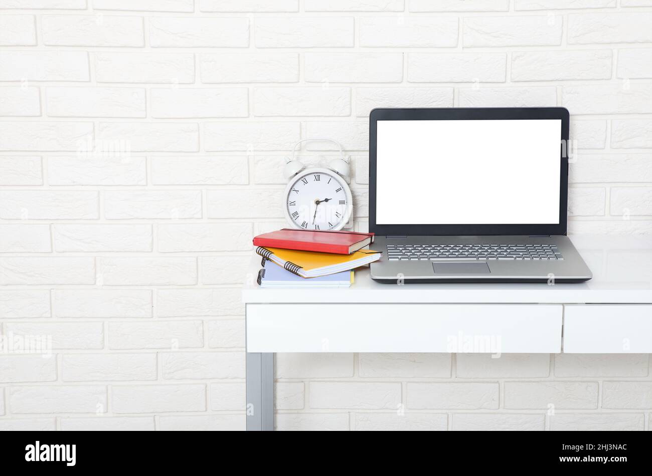 Education accessories on the table near brick wall. Empty computer and ...