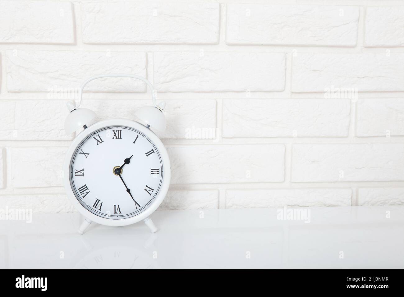 Retro alarm clock with twenty five minutes after one o'clock near brick ...
