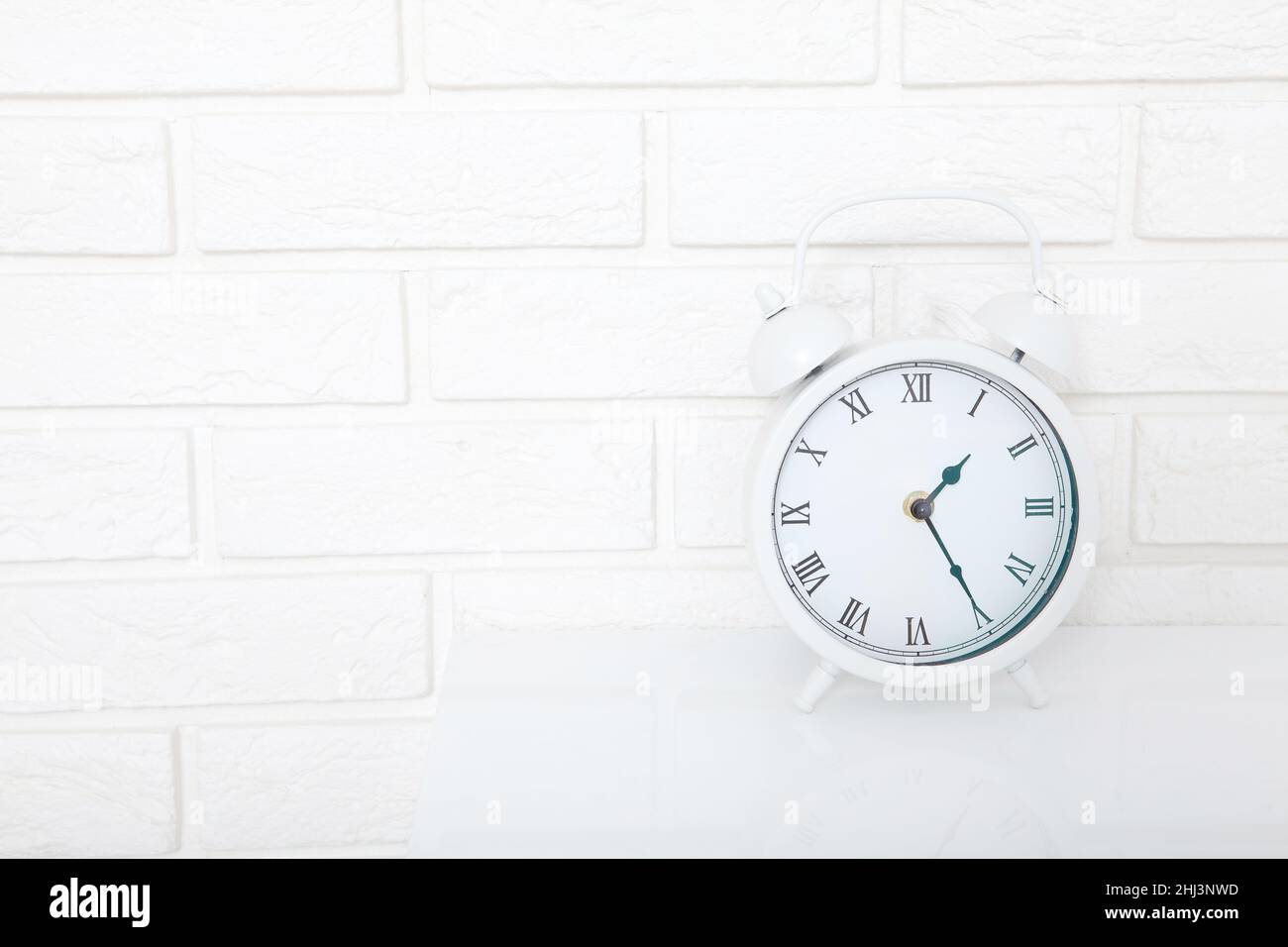 Retro alarm clock with twenty five minutes after one o'clock near brick ...