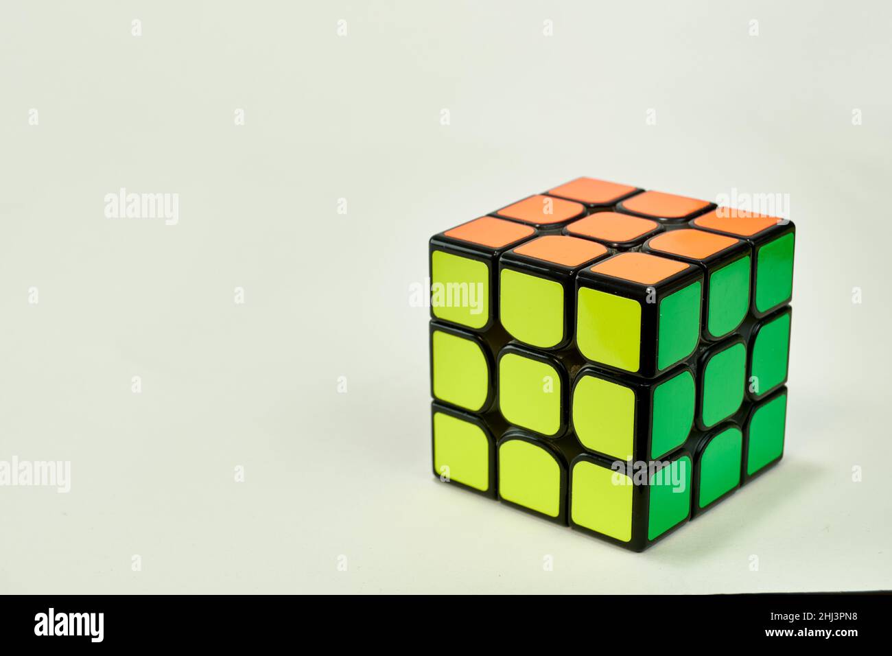 solved rubik's cube in yellow, green and orange on white background Stock Photo - Alamy