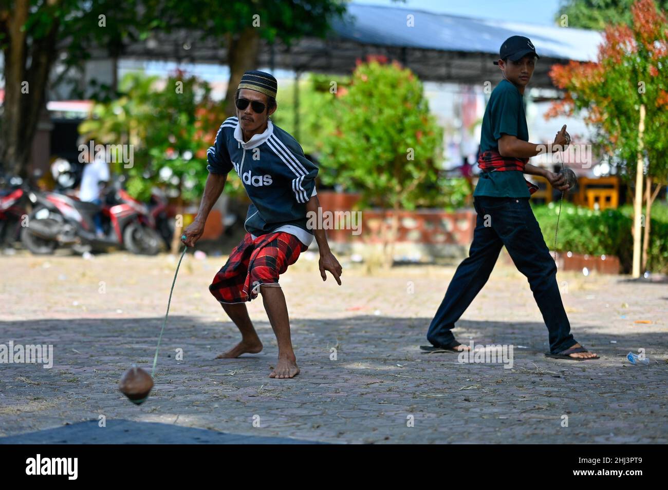 Two men are seen playing a traditional game called gasing or tops ...