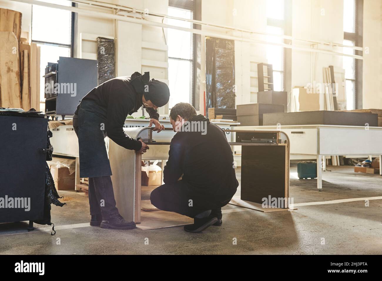Portrait of two male workers turned back to the camera, looking at a ...