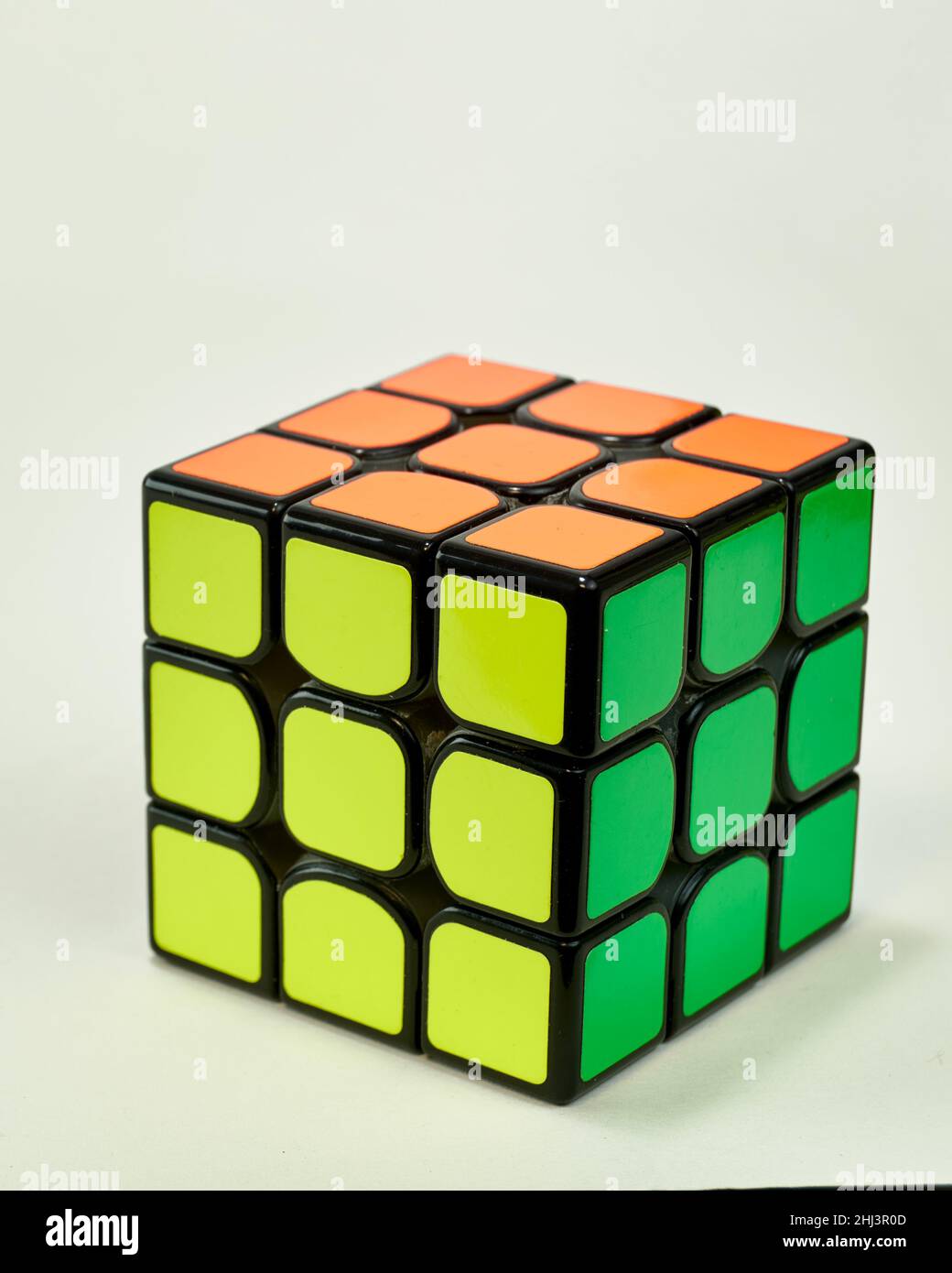 solved rubik's cube in yellow, green and orange on white background vertical Stock Photo - Alamy