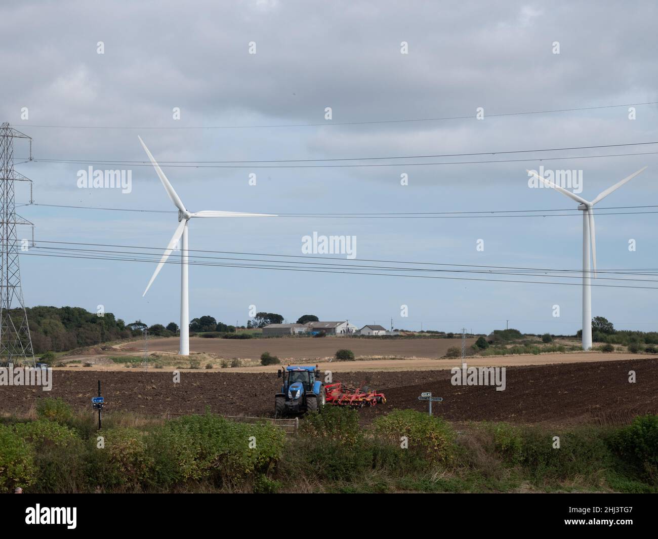 Tractor in field in front of wind turbines Stock Photo - Alamy
