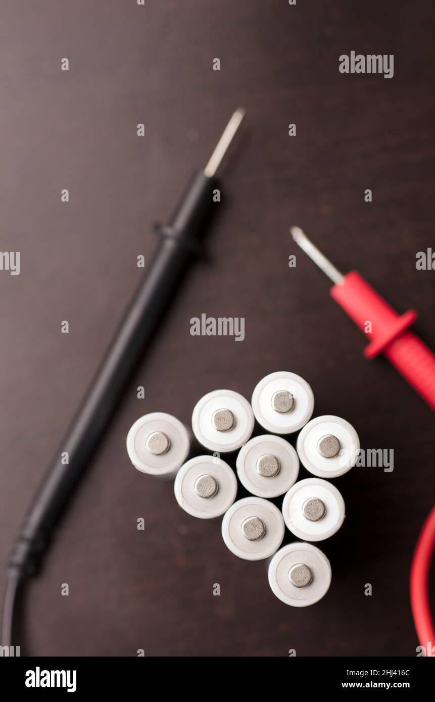group of batteries with multimeter, red positive pole, black negative ...