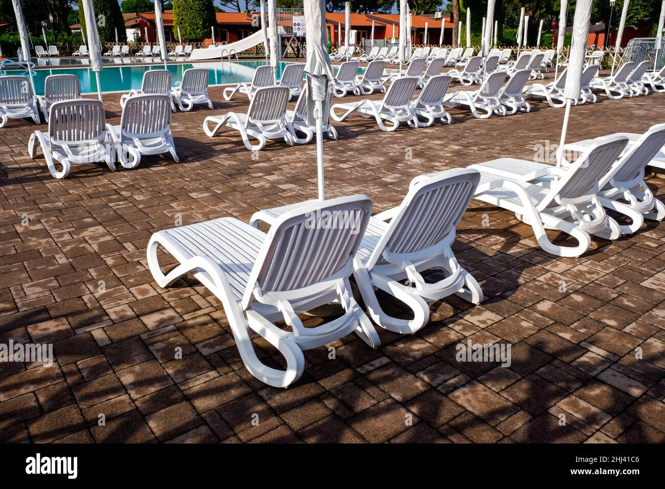 Empty plastic sunbeds without tourists in an outdoor swimming pool ...