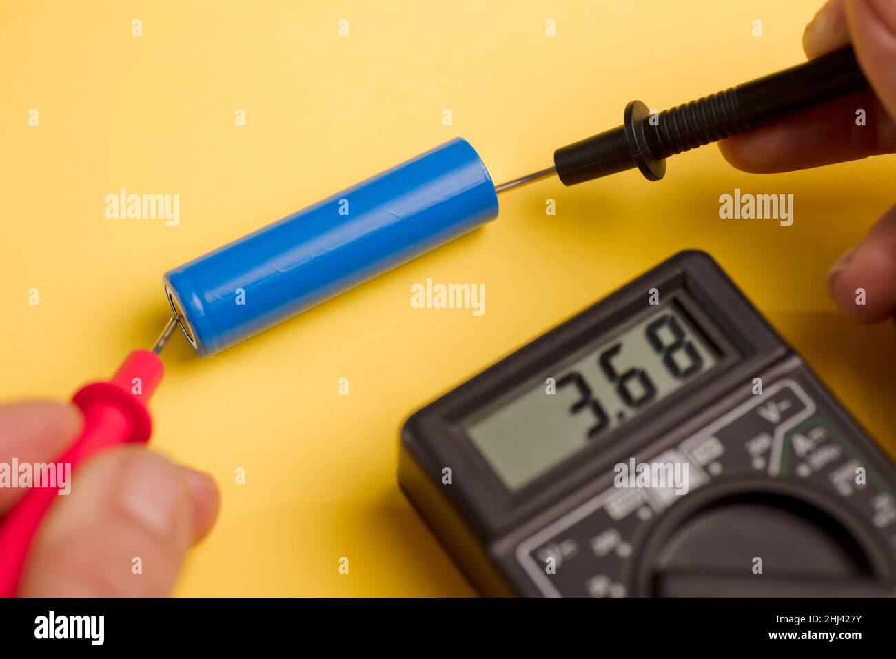 battery with volt calculator, multimeter in the hands of a man, red ...