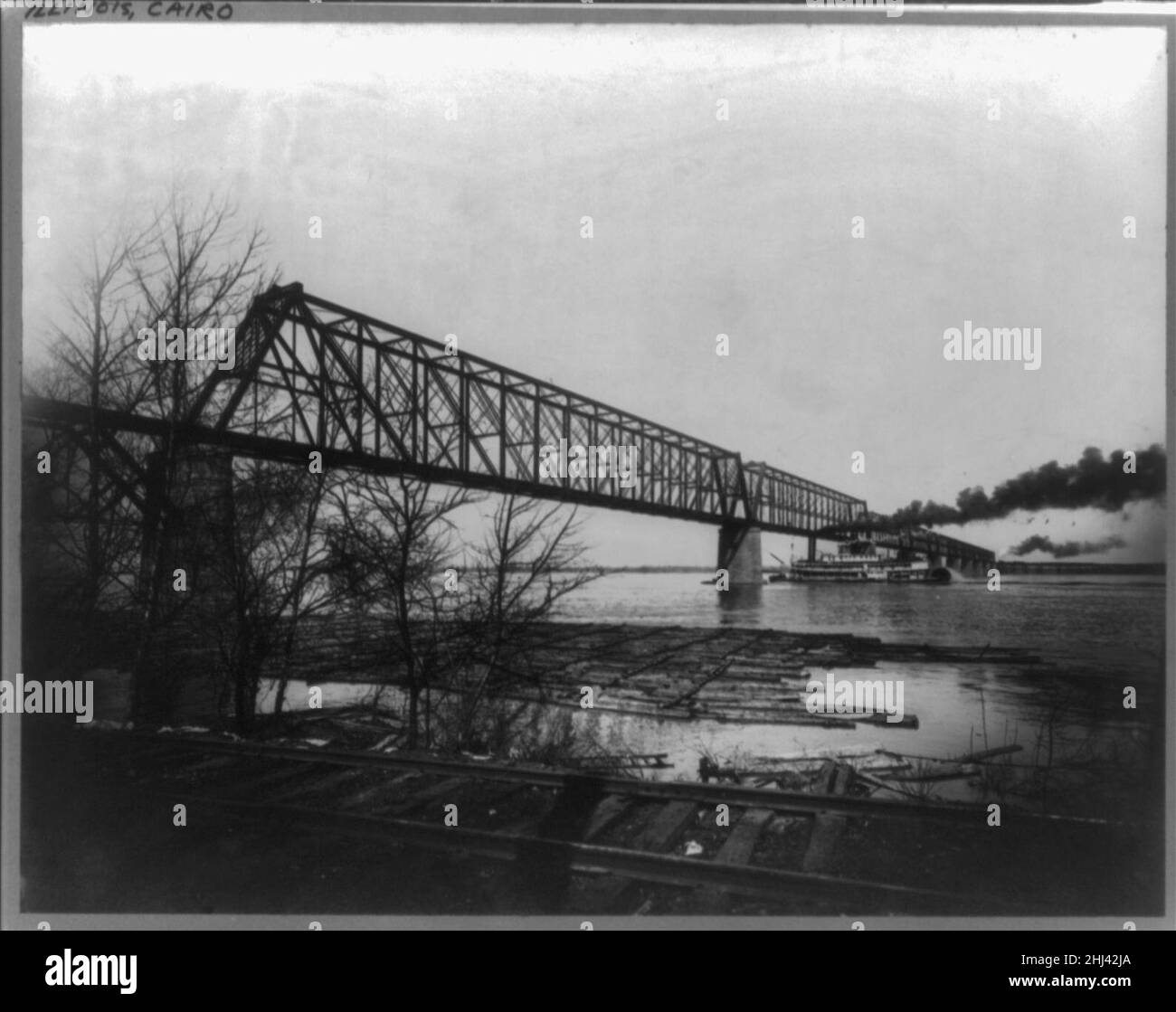 Stern-wheel riverboat passing under Illinois Central Railroad bridge ...