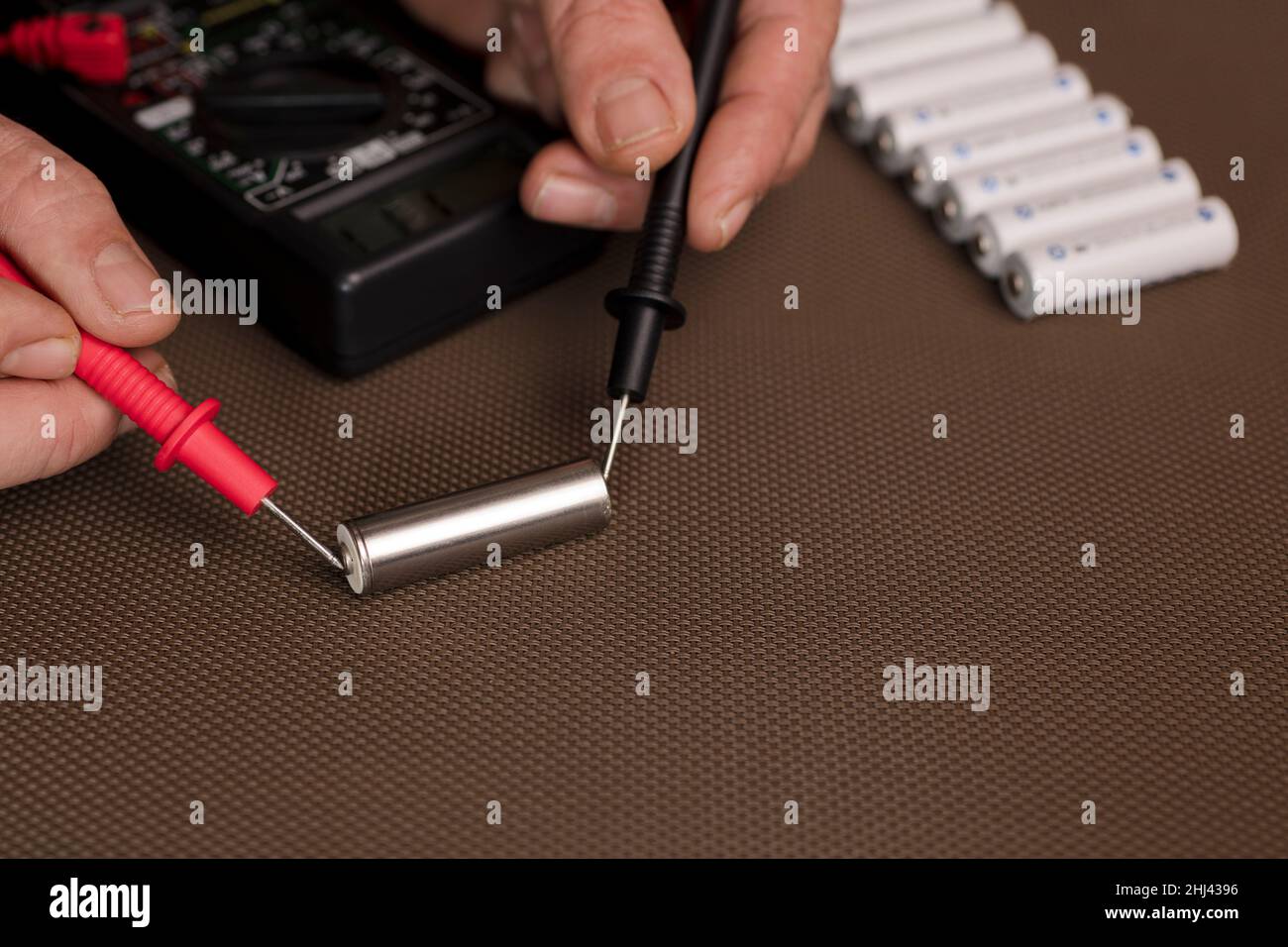 battery with volt calculator, voltmeter in the hands of a man, red ...