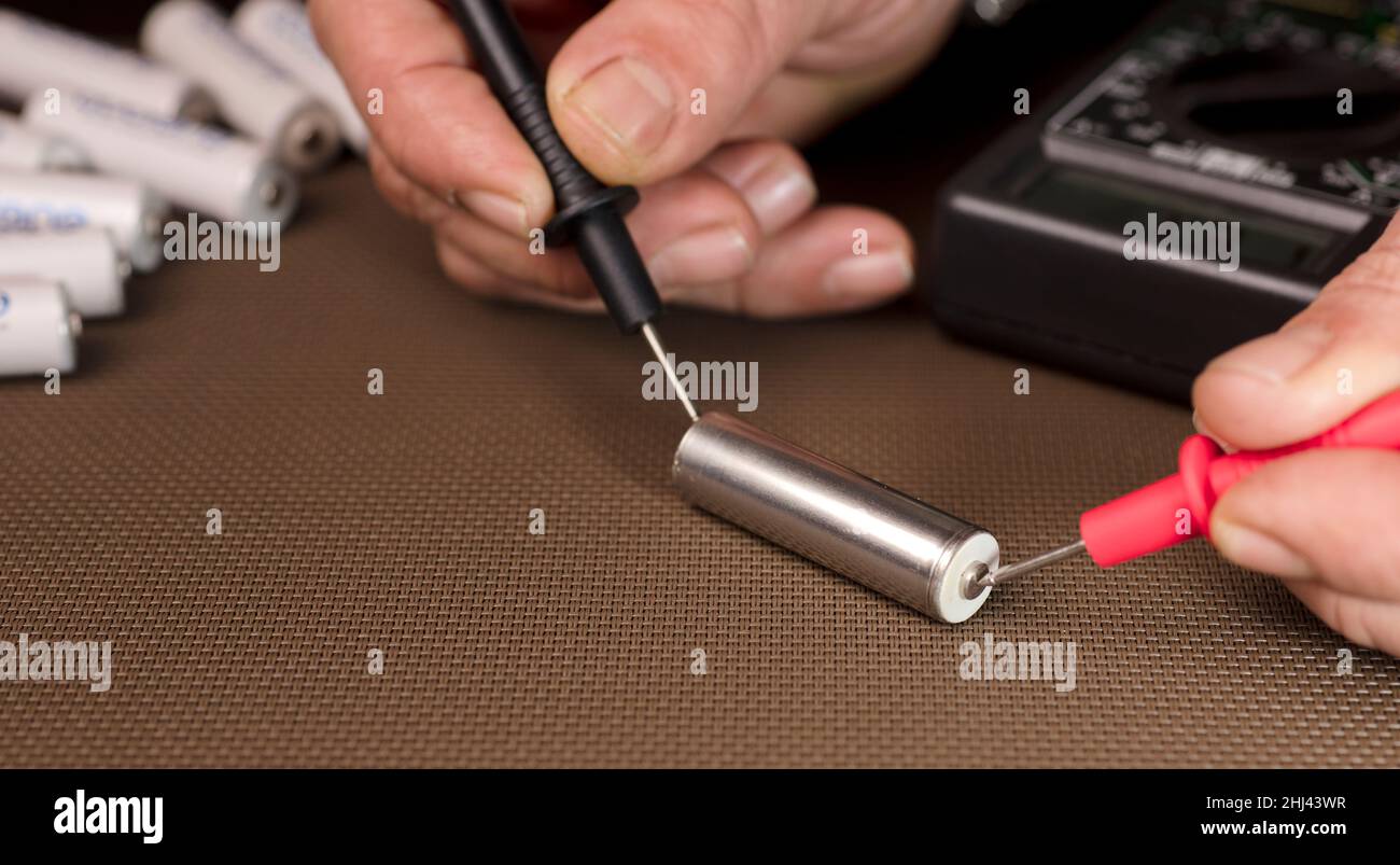 battery with volt calculator, voltmeter multimeter in the hands of a ...