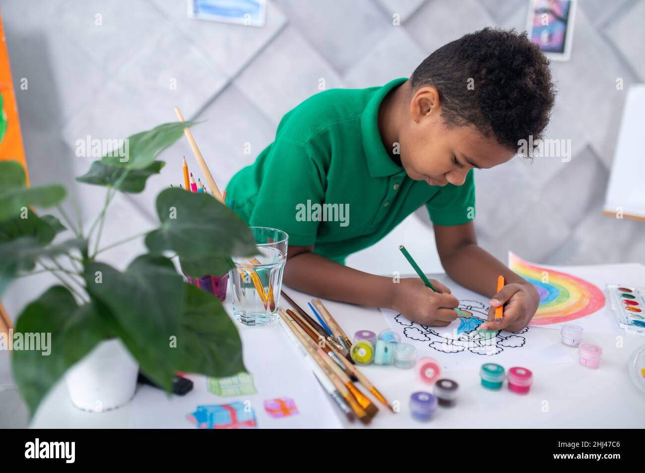 Boy drawing with color pencil standing at table Stock Photo - Alamy