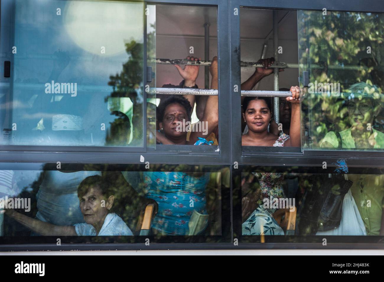 Bus load of women in a crowded bus in Havana, Cuba look towards the ...