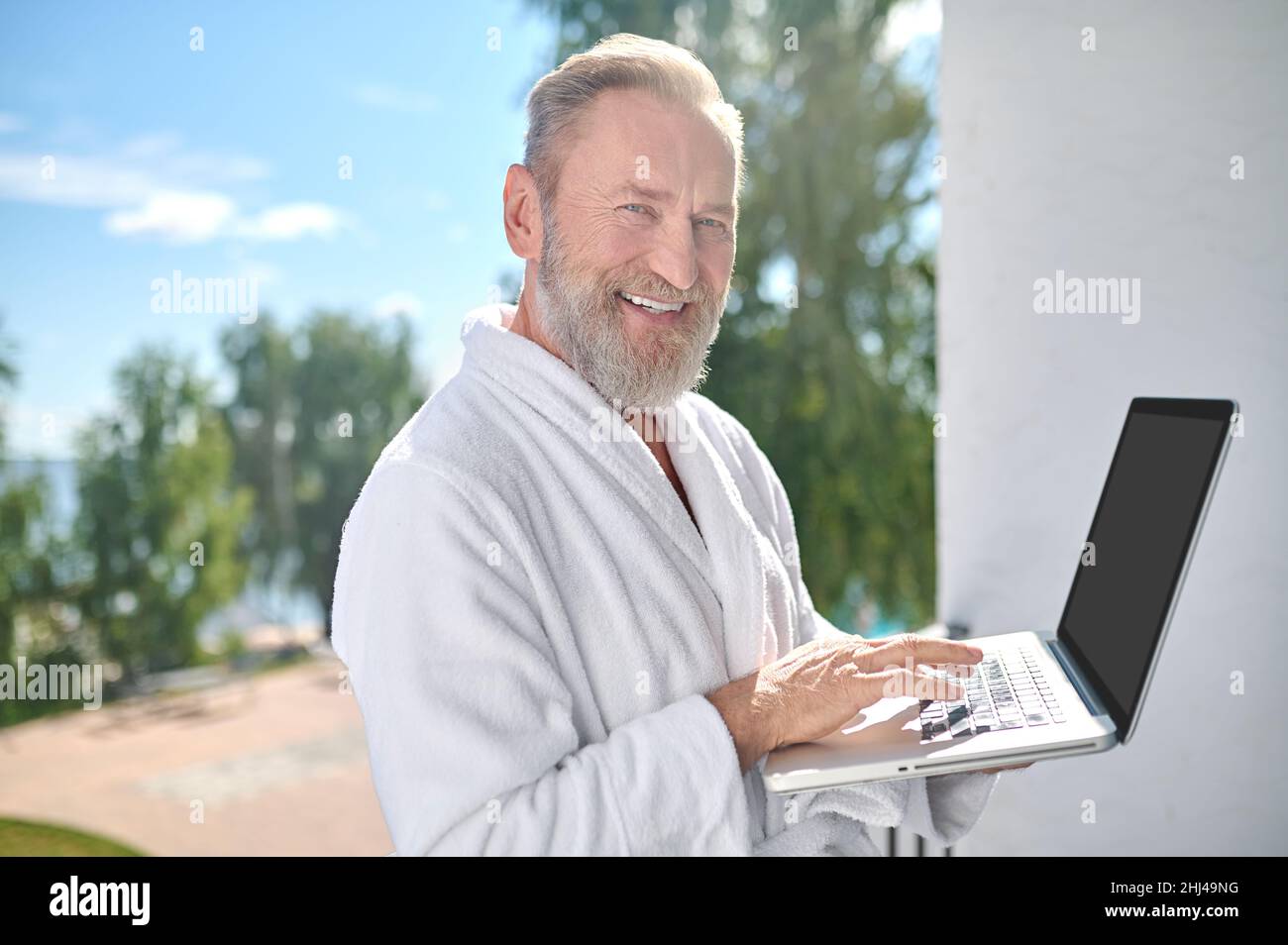 Male in the white bathrobe holding his portable computer Stock Photo ...