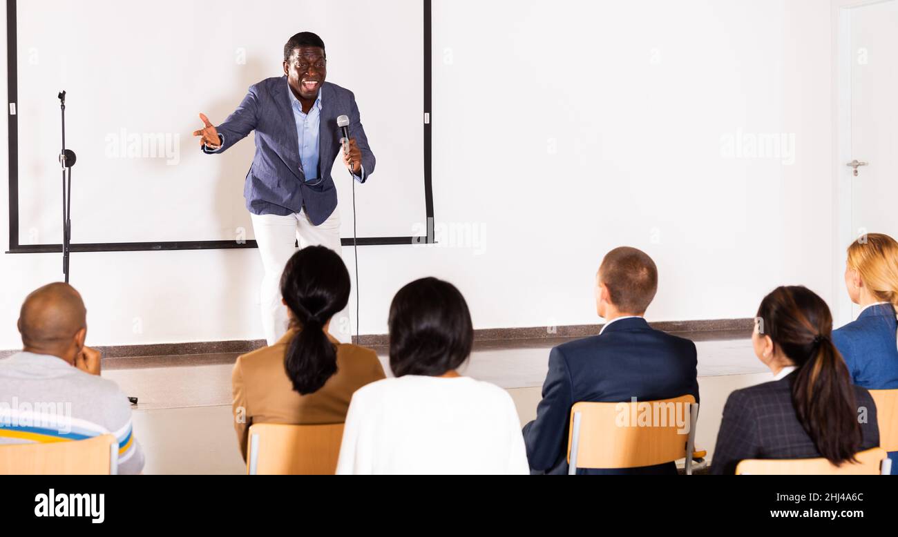 Expressive african american speaker with microphone on conference room ...