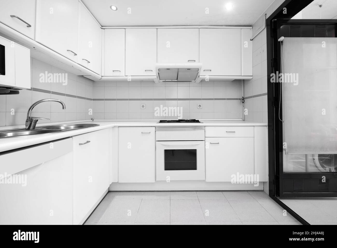 Conventional kitchen with white furniture, gray handles and white ...
