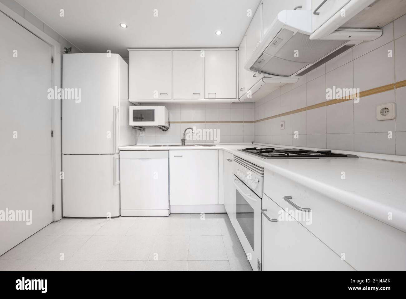 Conventional kitchen with white furniture and appliances, gray handles ...