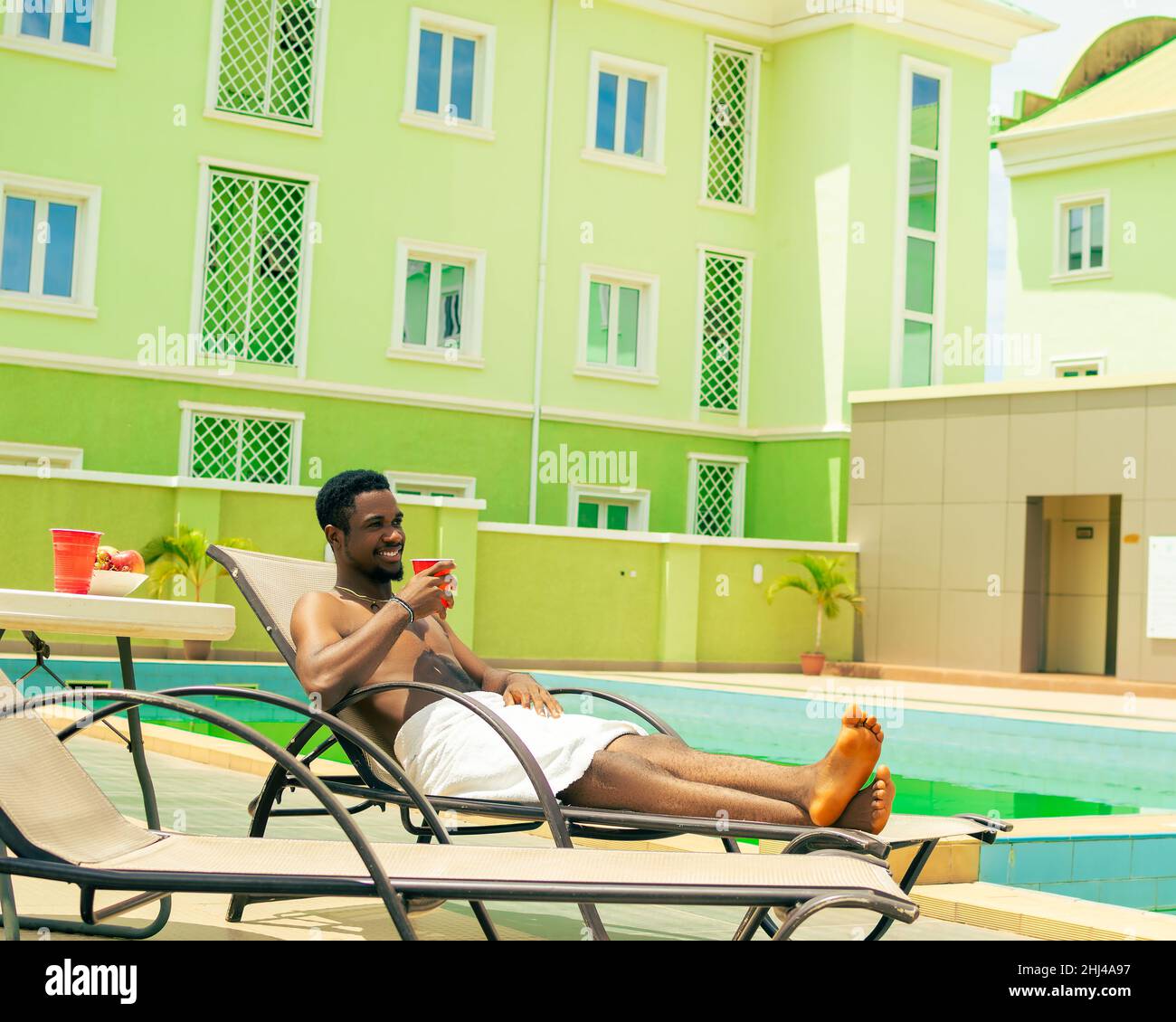 handsome african man seating beside a swimming pool relaxing Stock ...