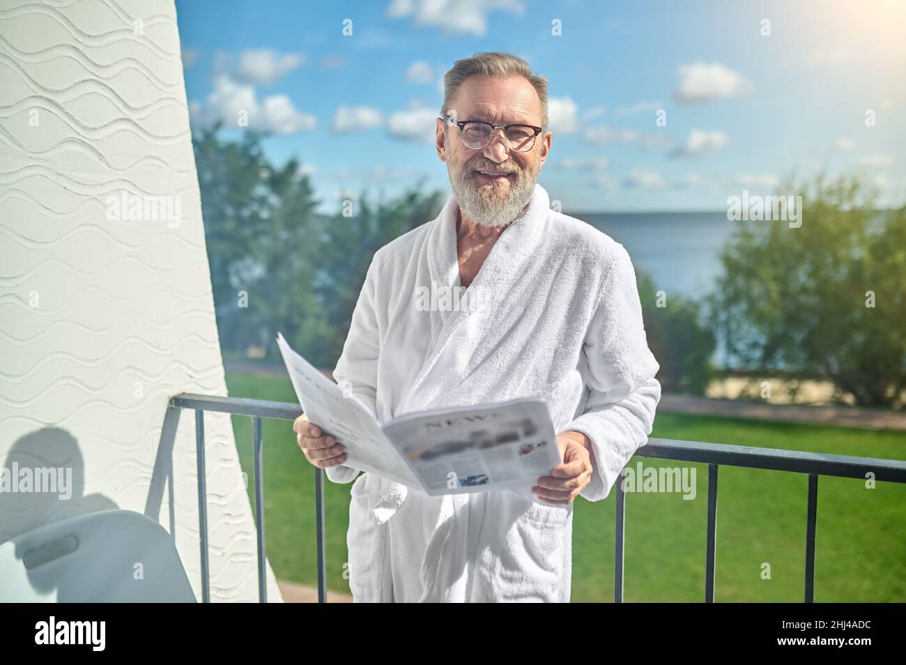 Man with the open newspaper leaning on the balcony railing Stock Photo ...