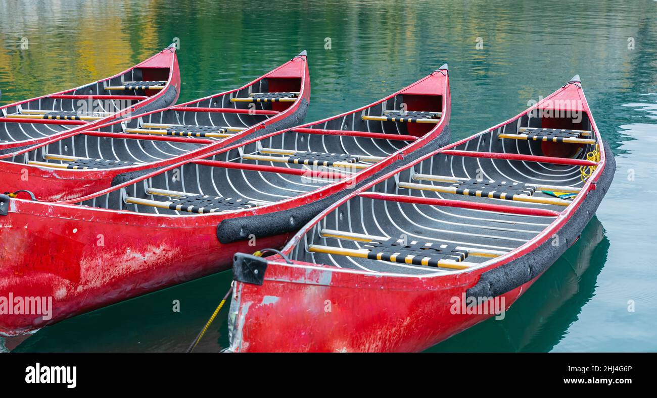 Red boats landing near the bank of the clear blue lake, reflected in ...