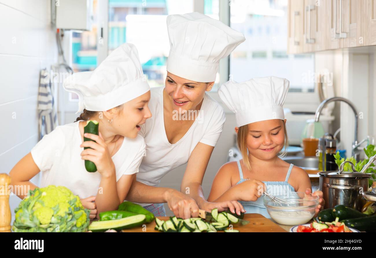 Little cooks learn with their mom how to cook a salad in the kitchen ...