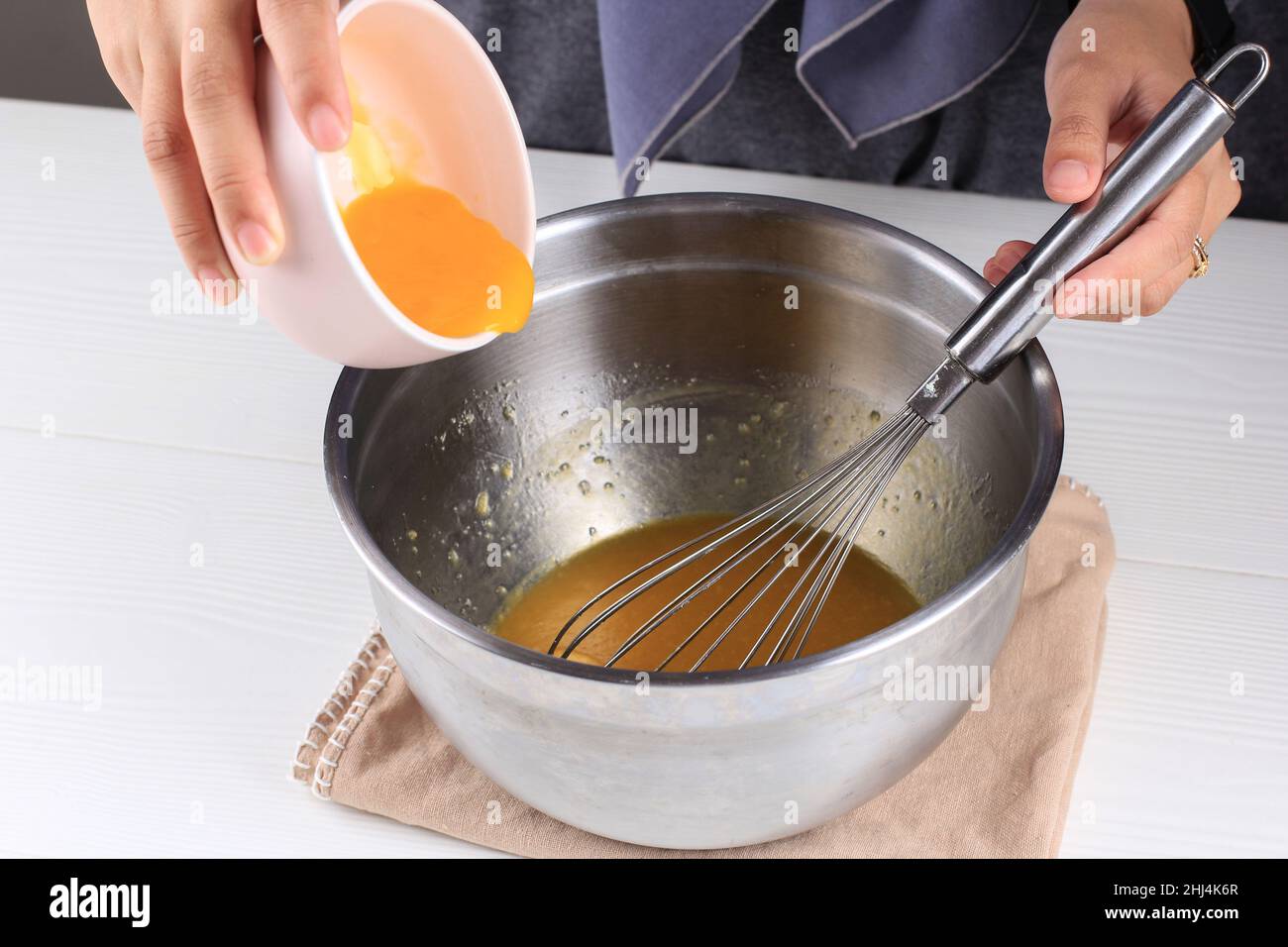 Female hands pour melted butter from a white bowl into crumbled ...