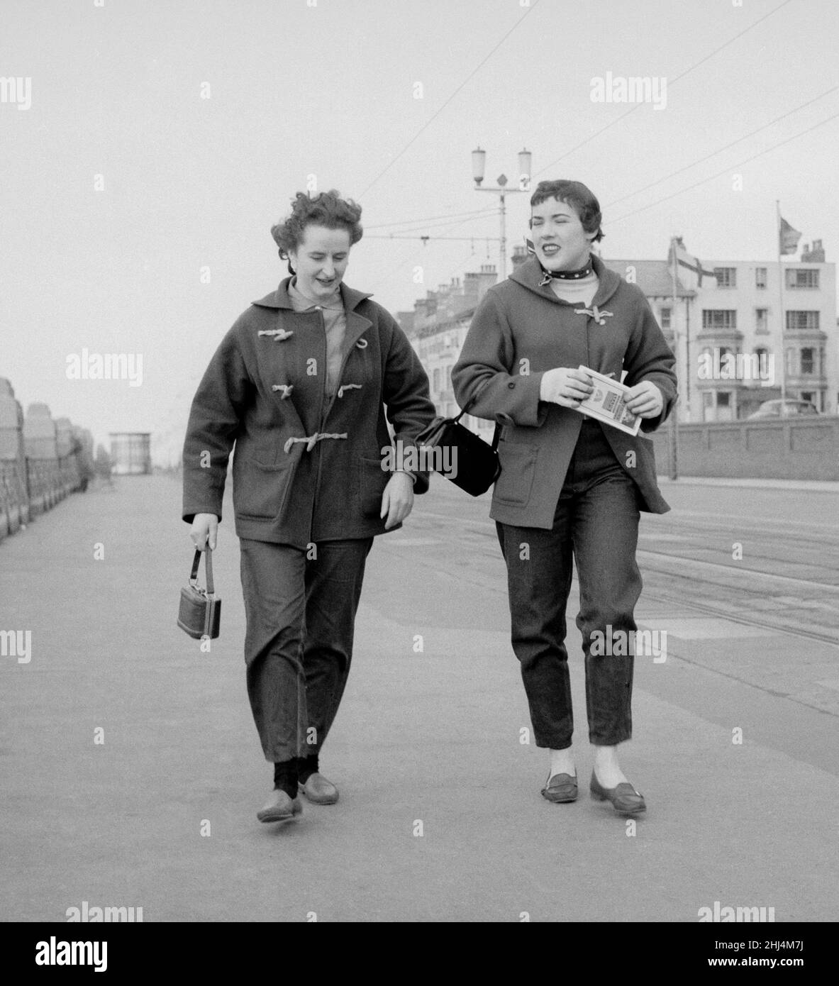 Racing drivers pat Moss and Ann Wisdom aged 21, take a brisk walk along ...