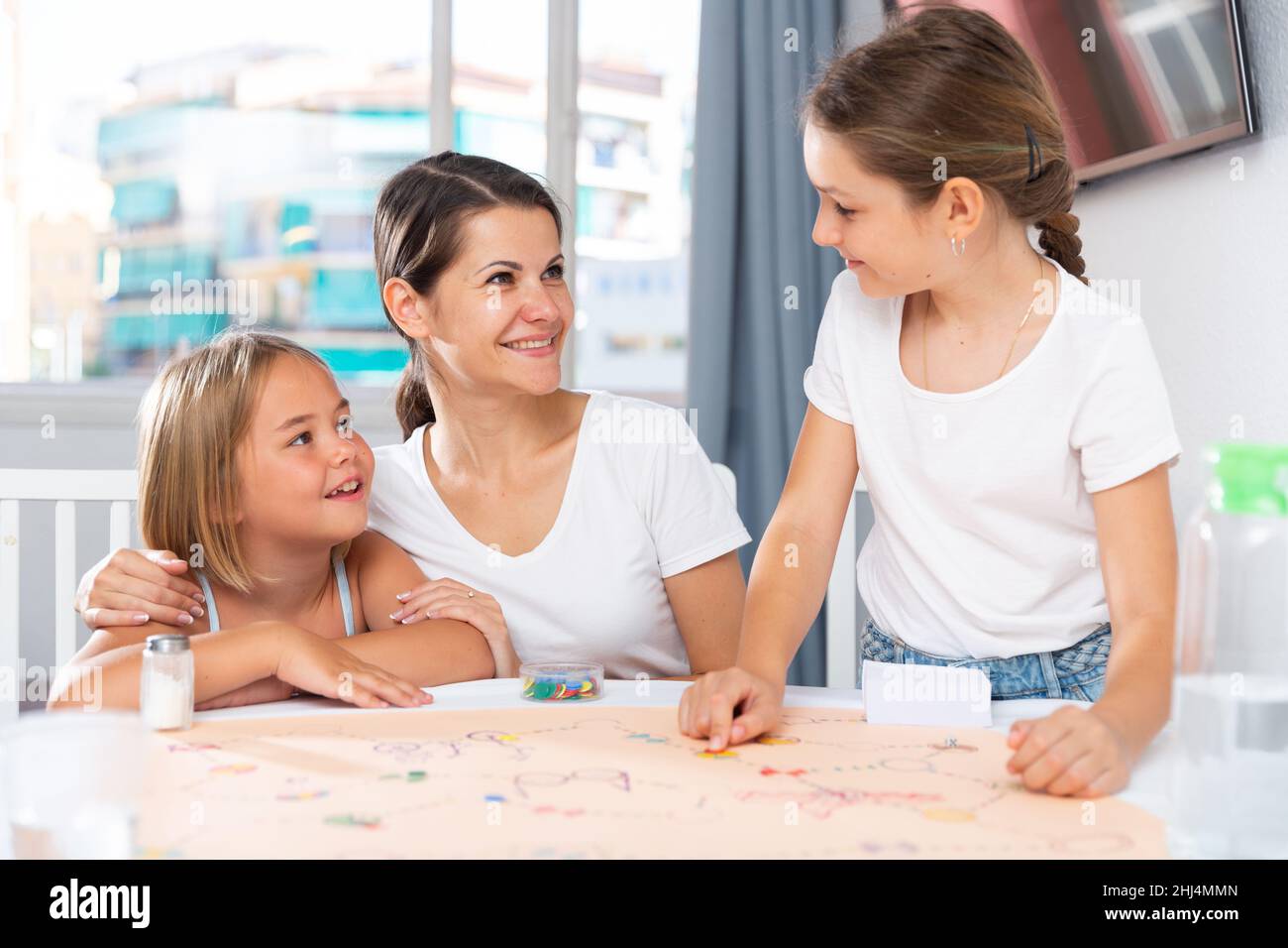 Mom with two daughters play board game at the table Stock Photo - Alamy