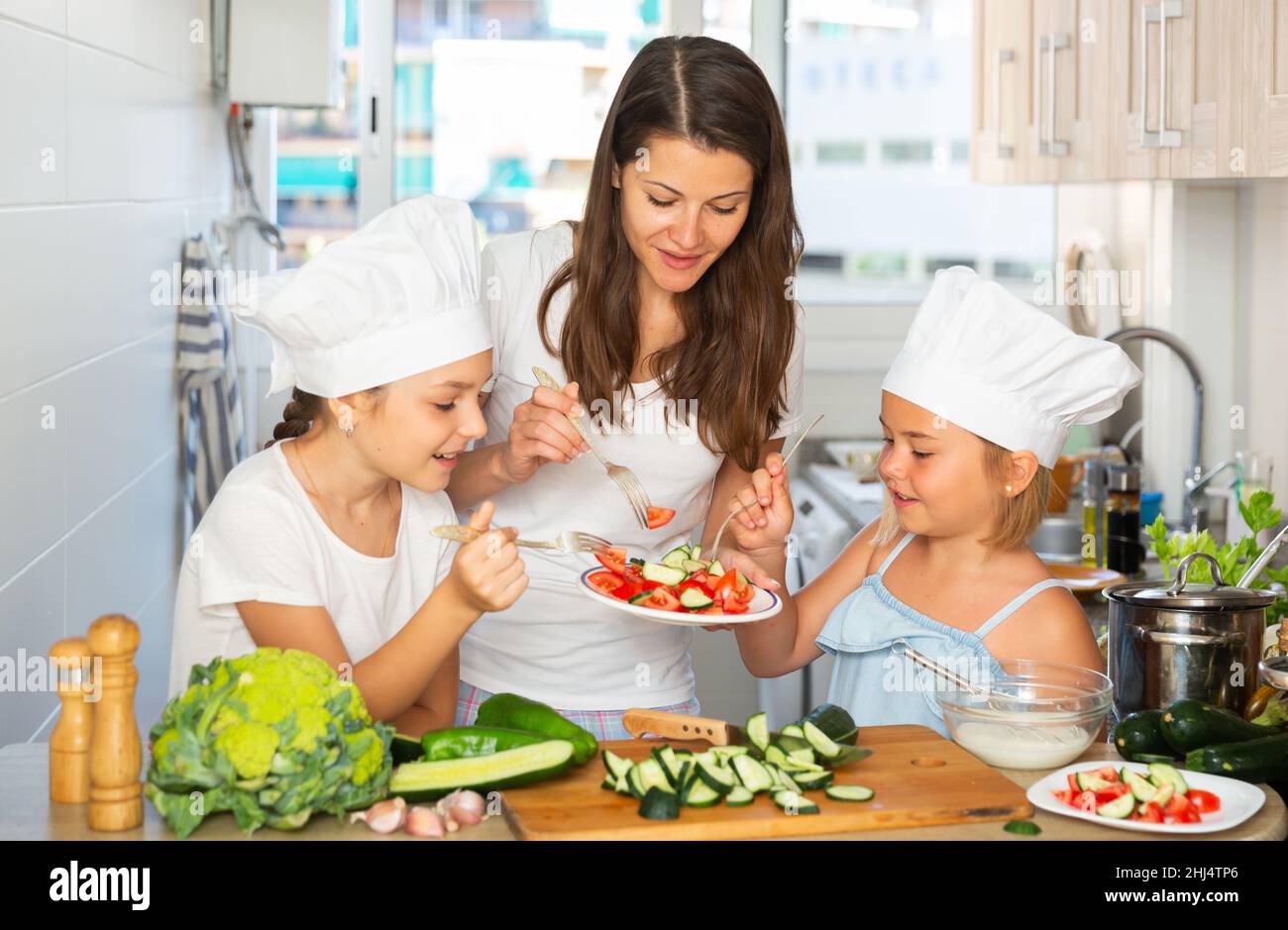 Little cooks learn with their mom how to cook a salad in the kitchen ...