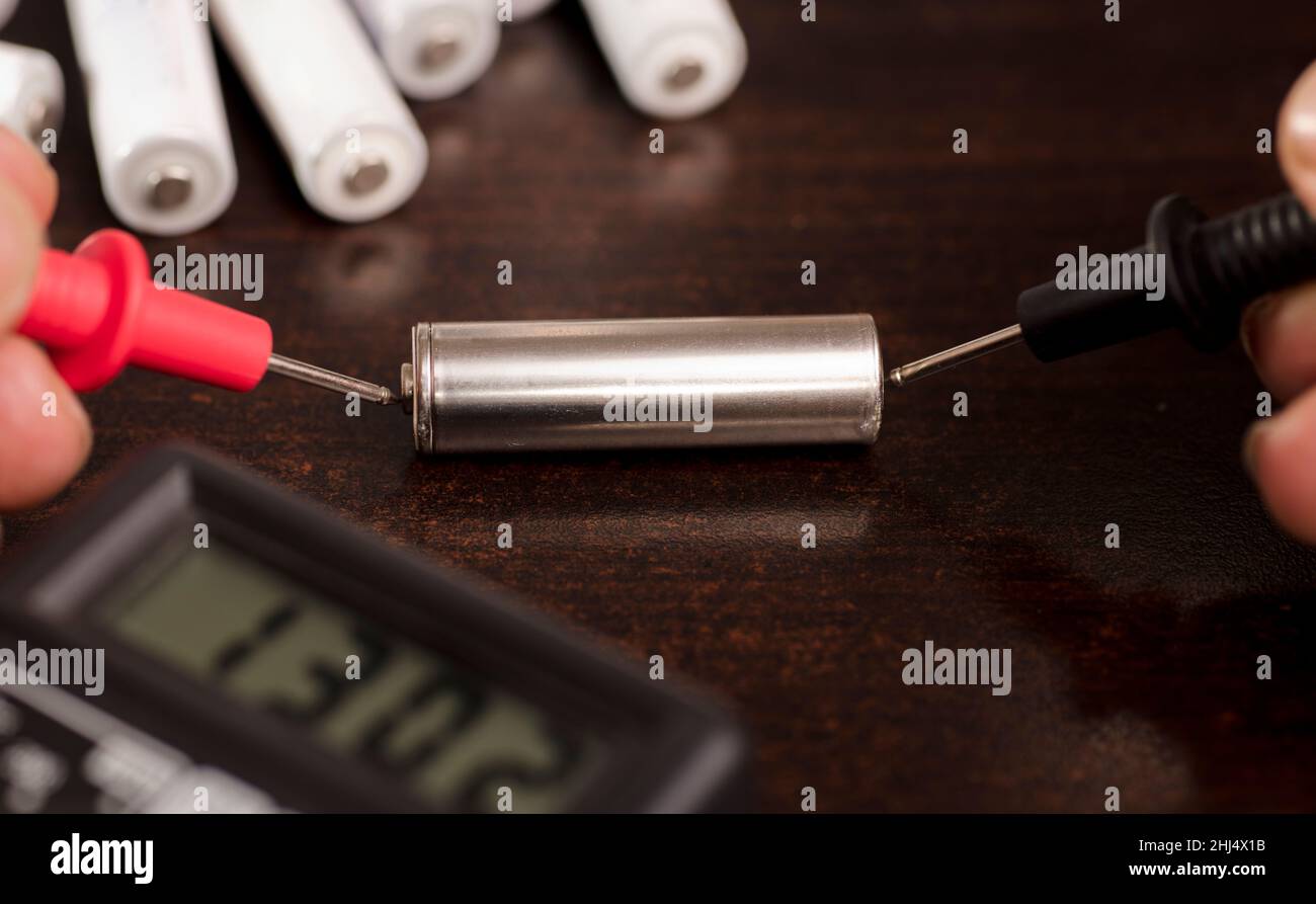 battery with volt calculator, voltmeter in the hands of a man, red ...