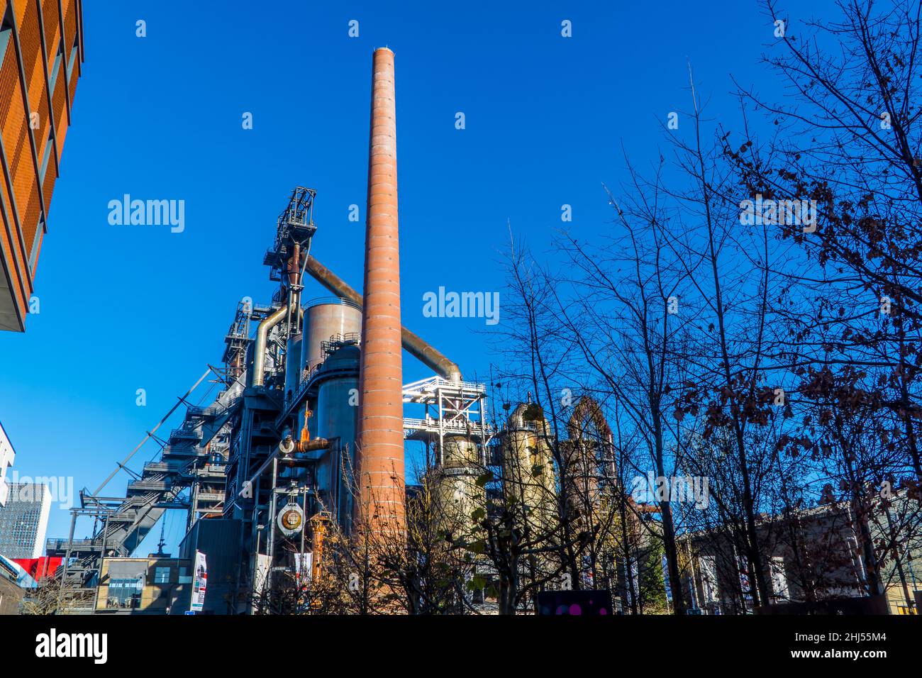 Low angle shot of an old steel factory tower chimney and modern ...