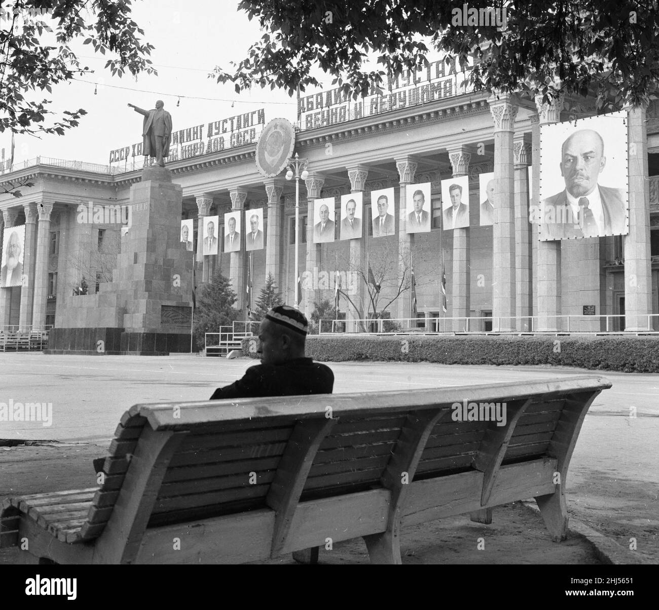 A man sits on a public bench in a deserted square in the Soviet city of ...