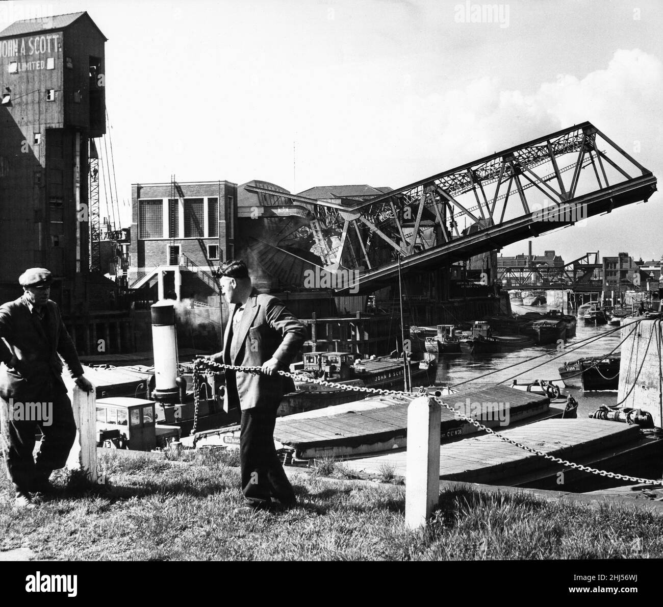 Workman repair the railings on Victoria Dock basin as in the background ...