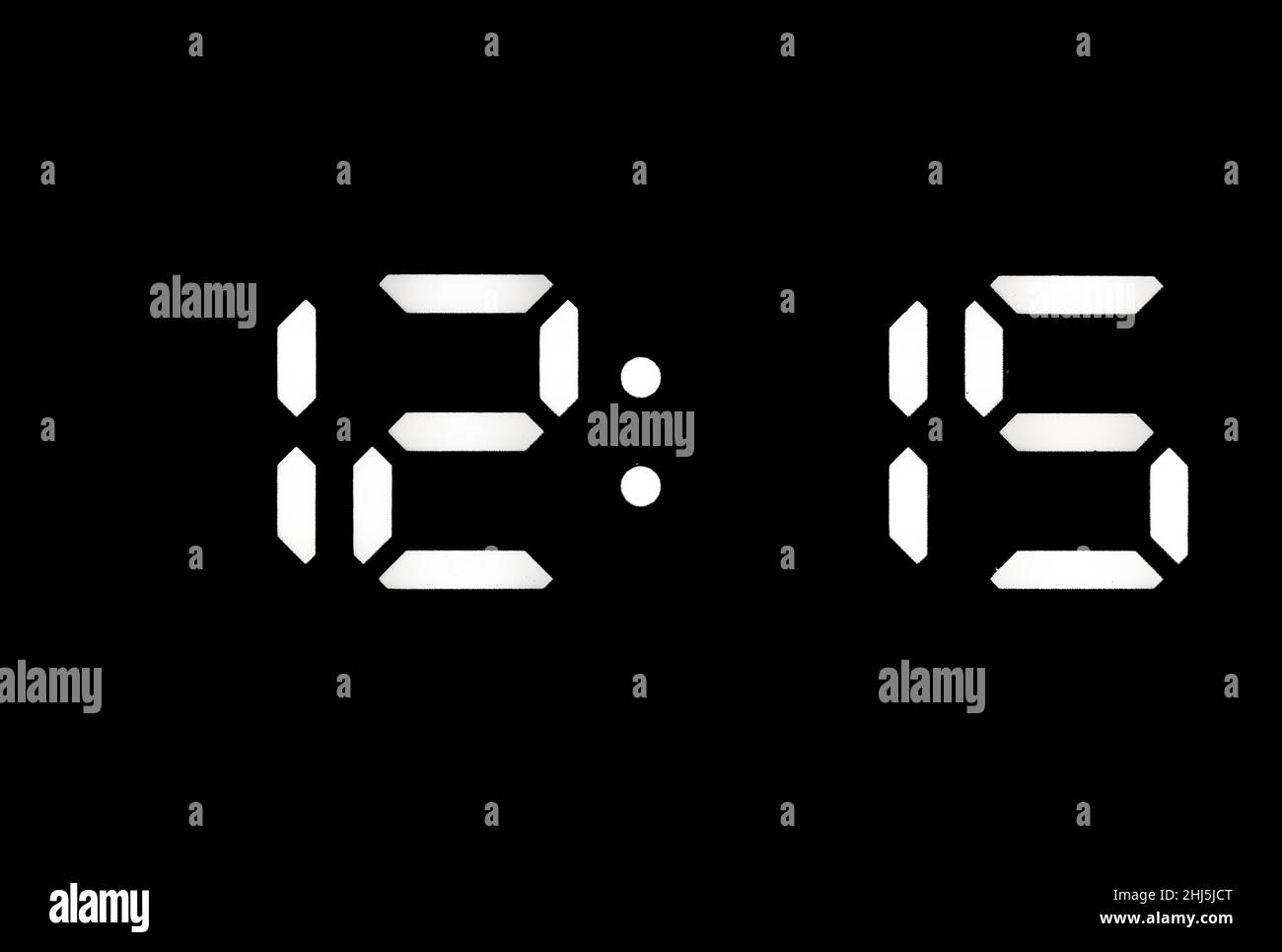 Real white led digital clock on a black background showing time 12:15 ...