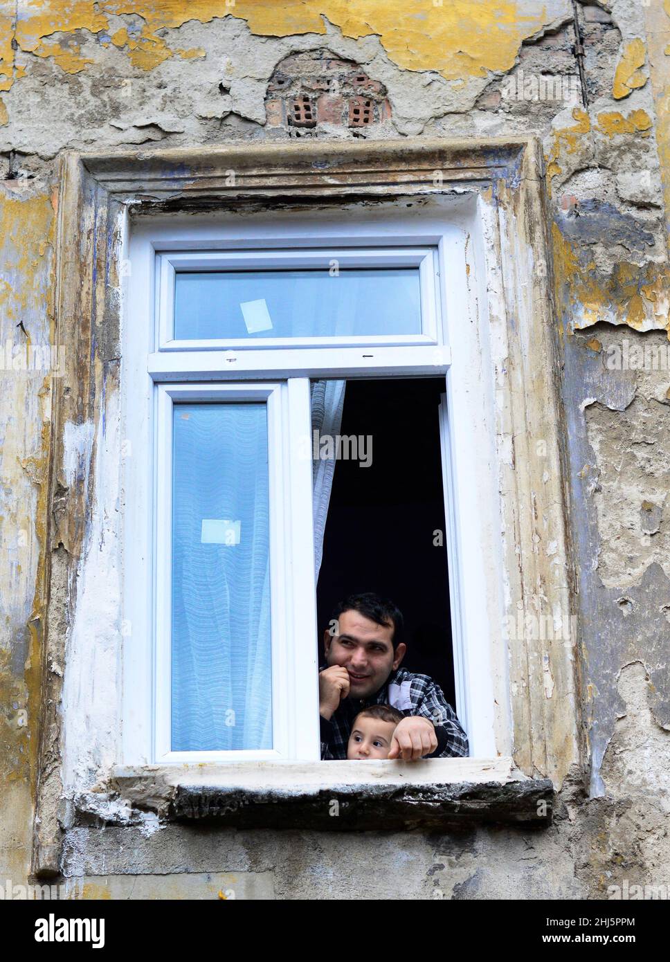 Father and his son looking out the window in their home in Istanbul ...