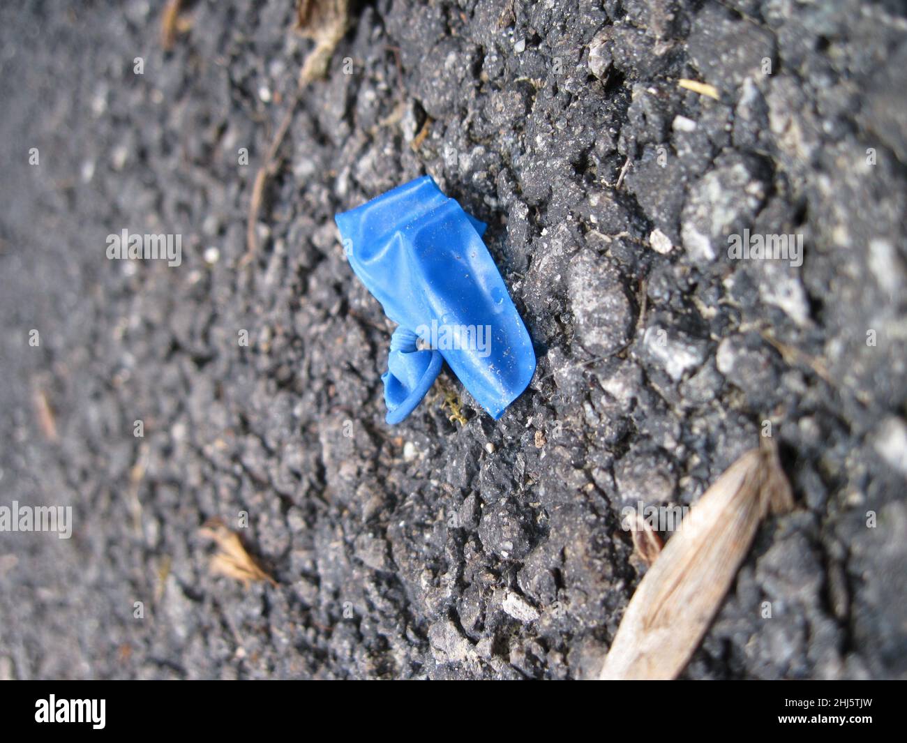 Blue popped balloon on the ground Stock Photo - Alamy