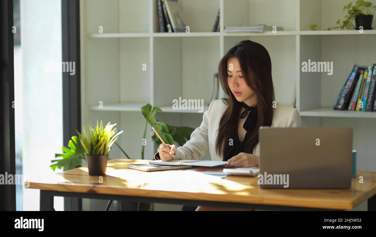 Beautiful Asian female business worker working at her office desk ...