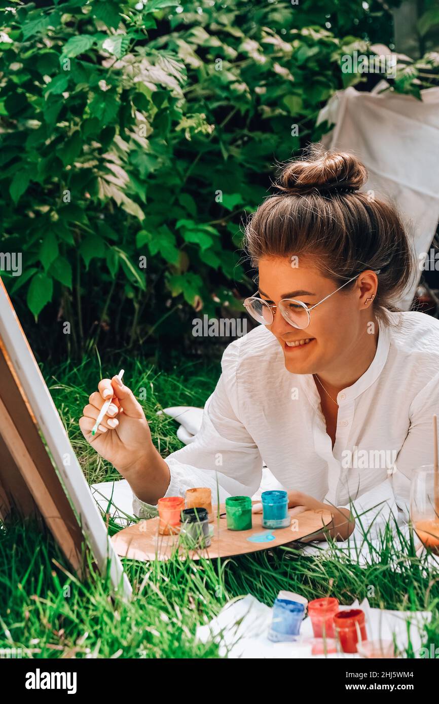 Artist painting on the easel outdoors in the garden. Open air outdoor ...