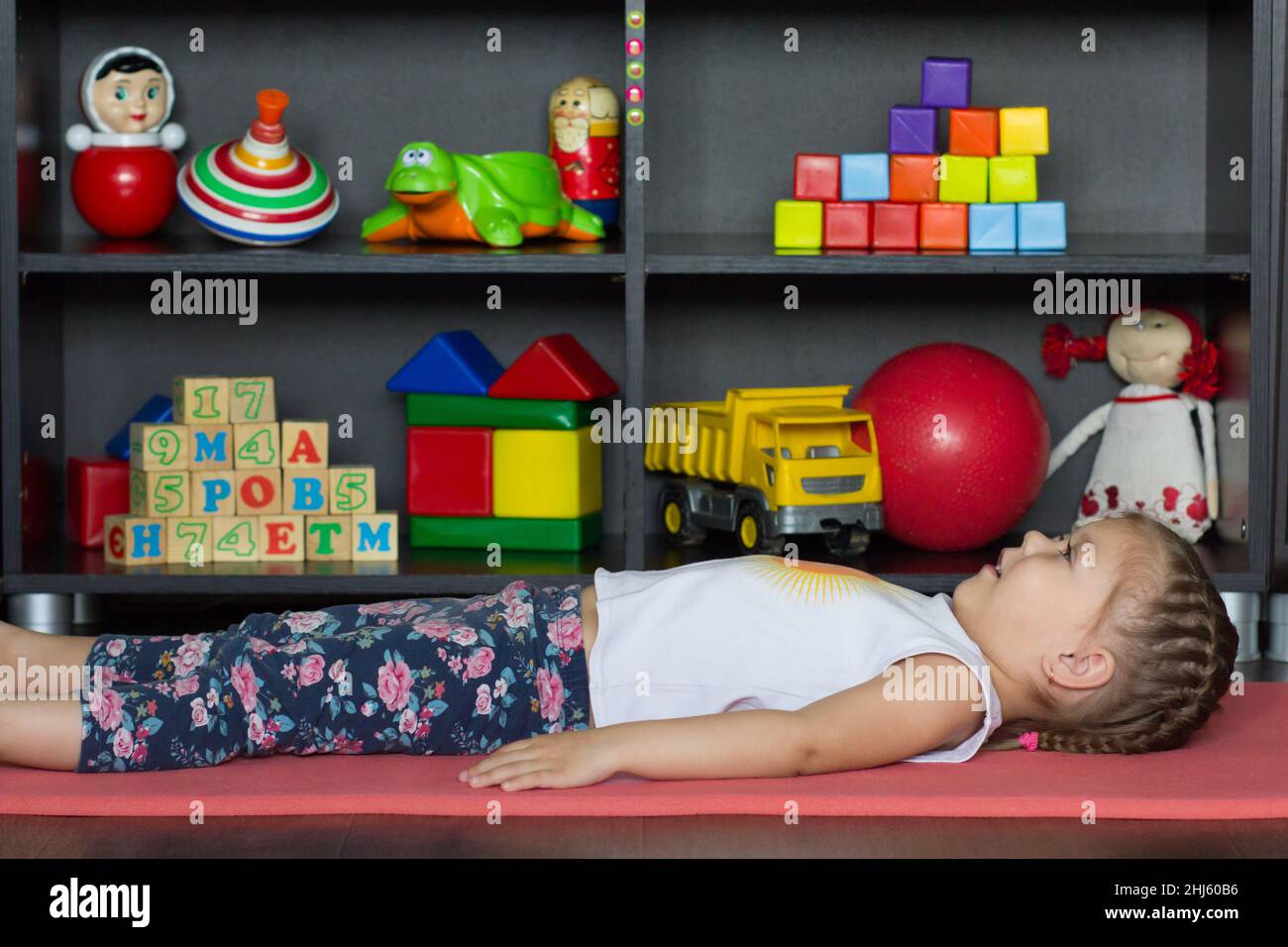 Little girl making yoga pose or exercise as lie on back in flat ...