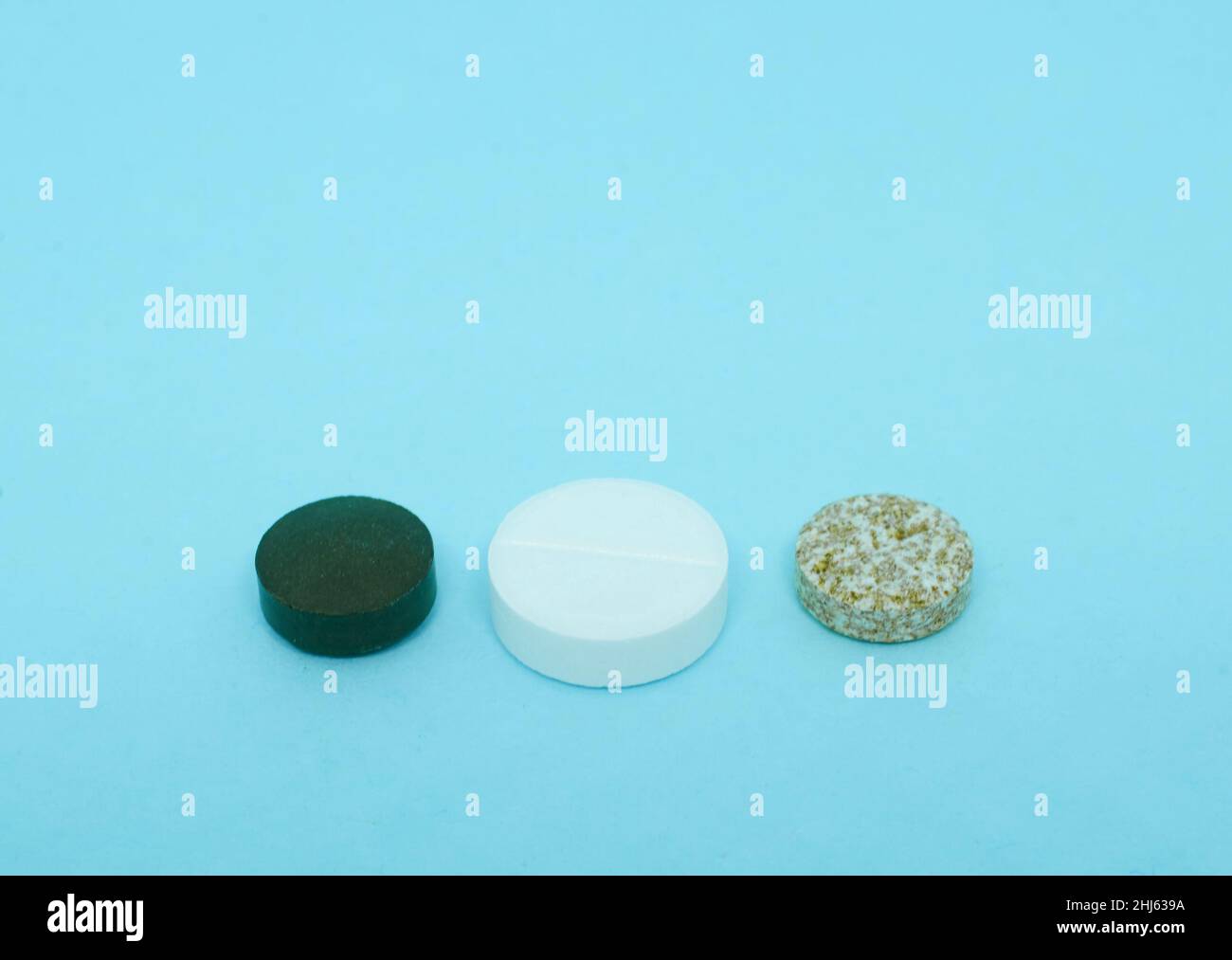 Green, white and mottled tablets lie on a blue background, copy space ...