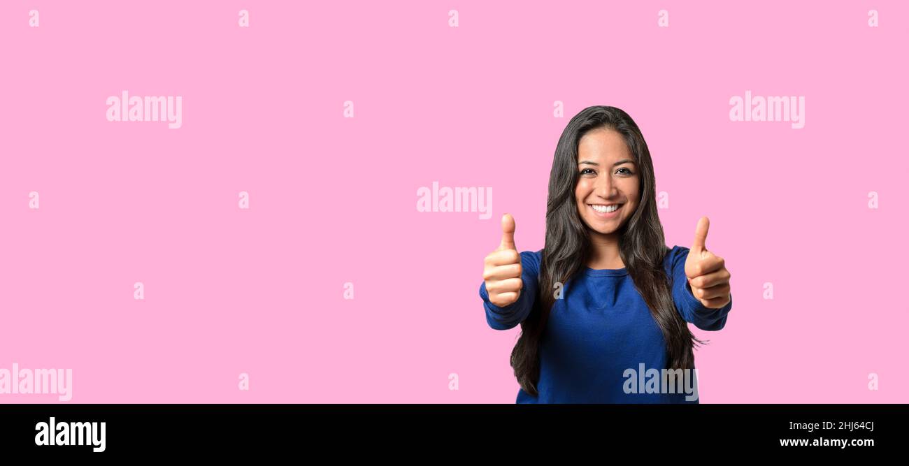 Elated successful young woman giving a double thumbs up with a beaming ...