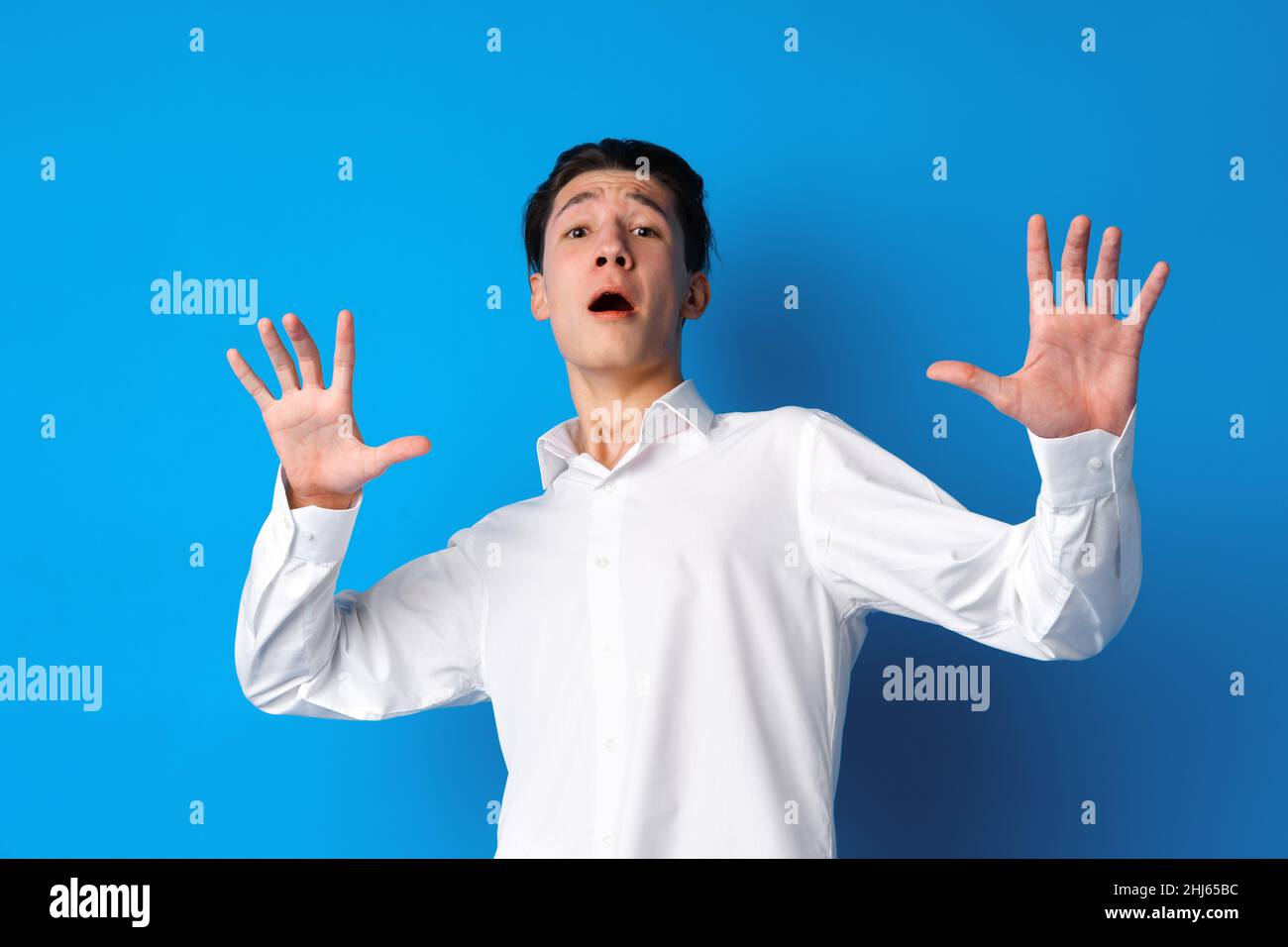 Portrait of unhappy teen boy looking scared on blue background Stock ...