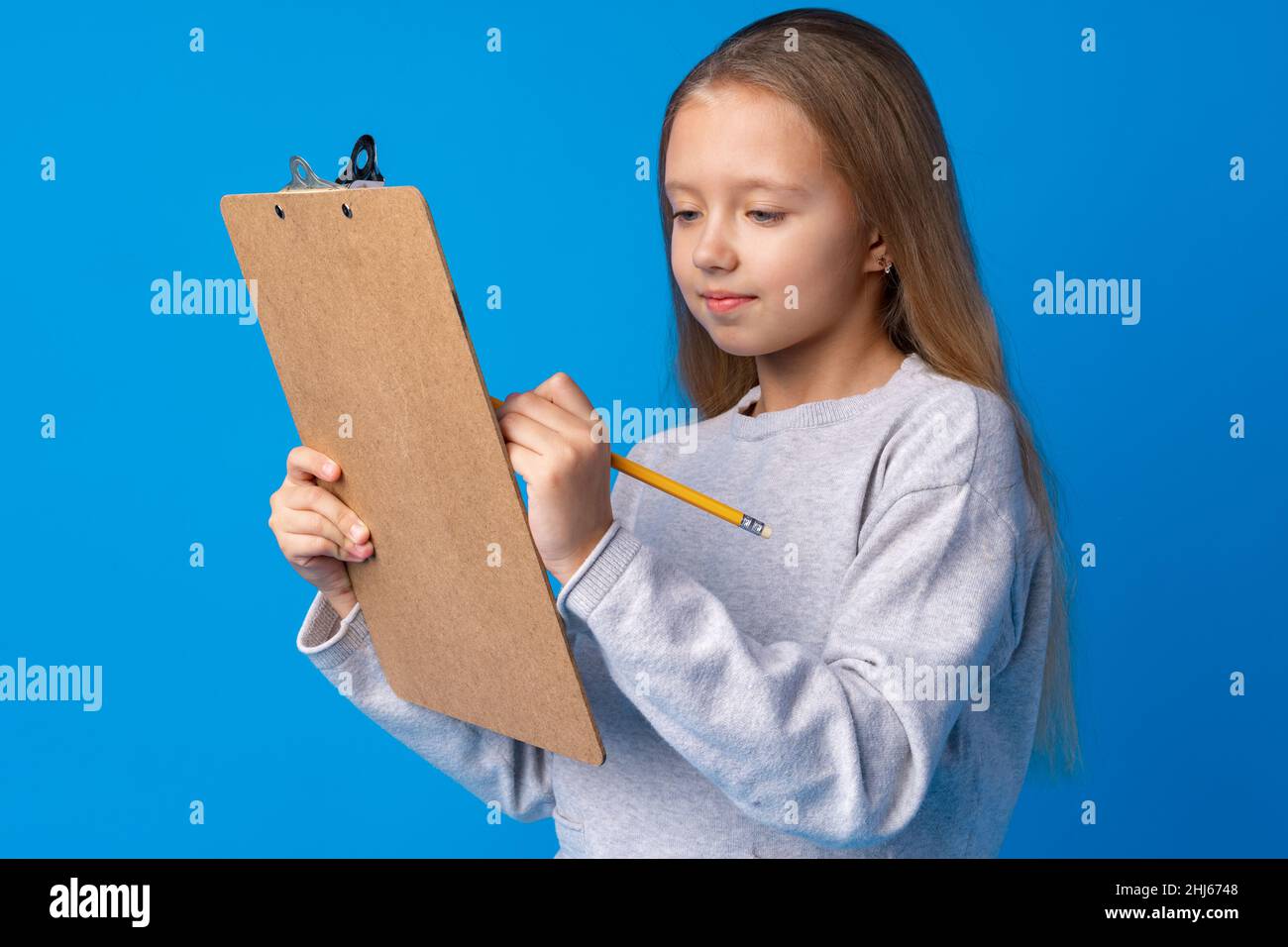 Portrait of little cute girl making notes against blue background Stock ...