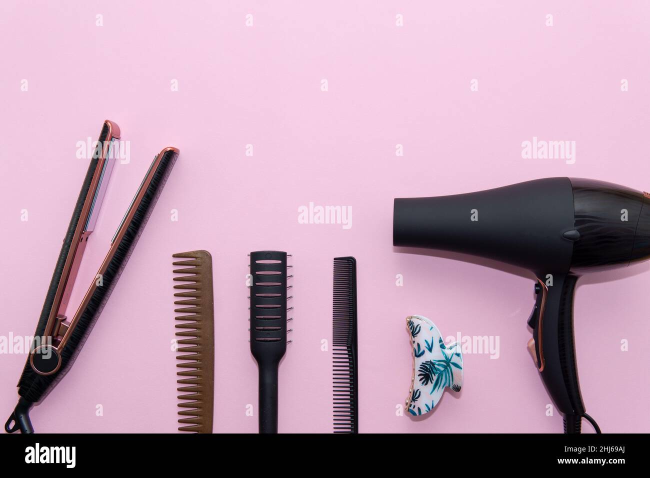 Top view of black hair straightening iron, a hairdryer and some combs ...
