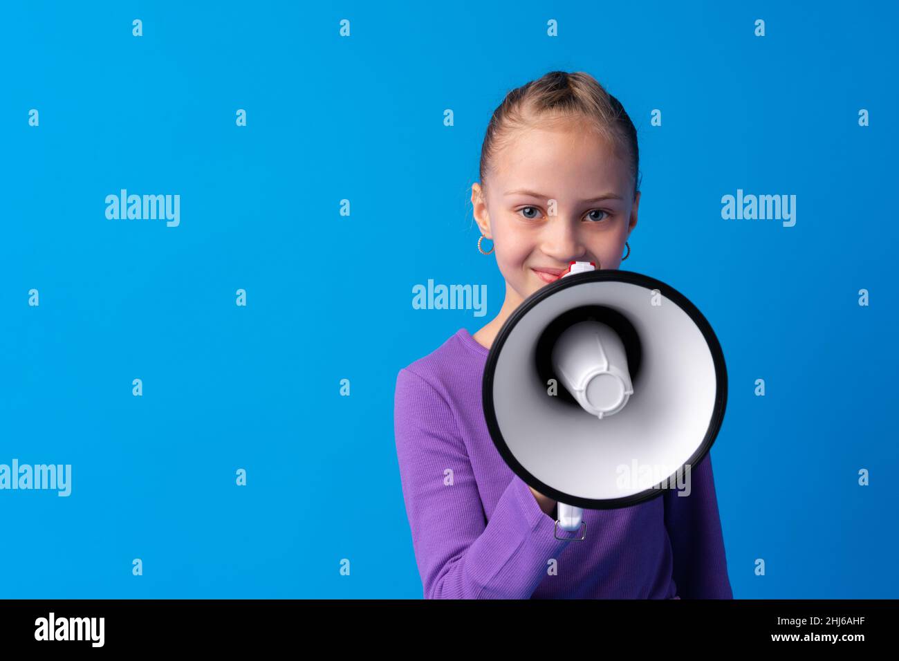 Child girl using megaphone against blue background Stock Photo - Alamy